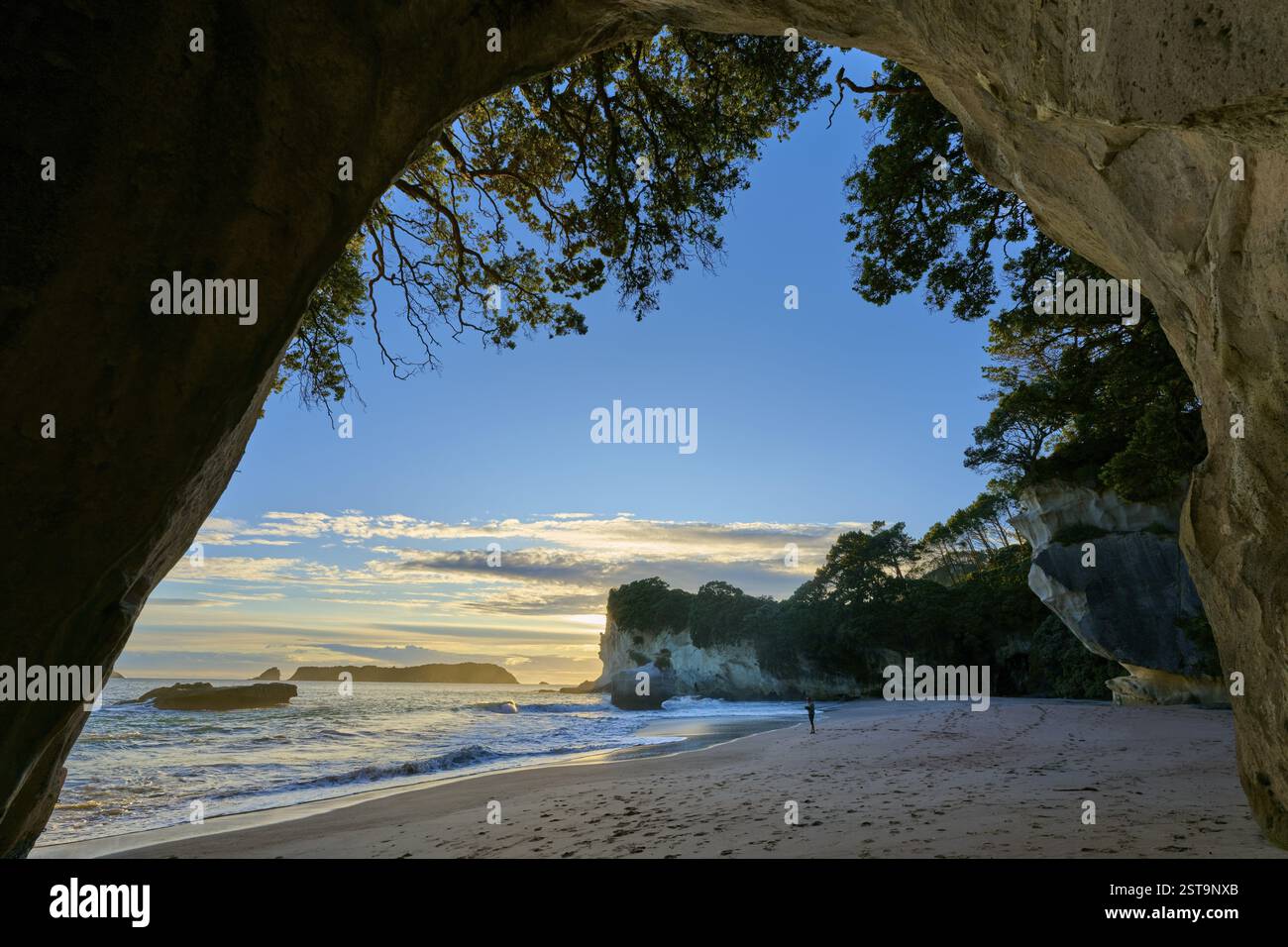 Romantic beach scene at sunrise with view from a cave, sea and trees ...