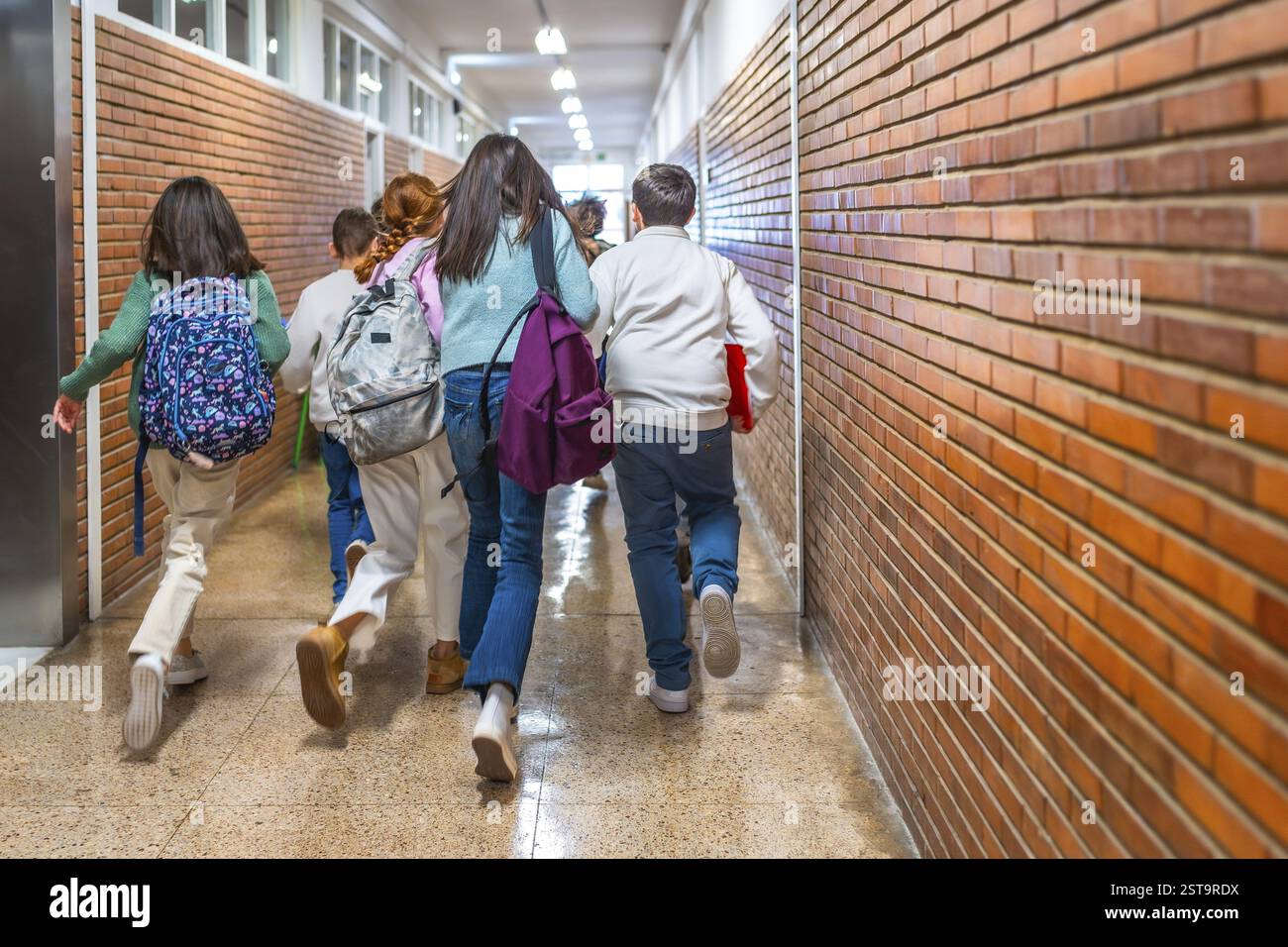 Elementary school students joyfully running down the hallway after the ...