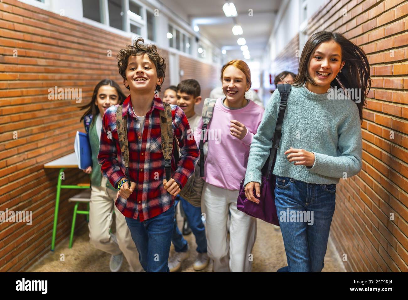Cheerful students running through the school hallway, filled with ...
