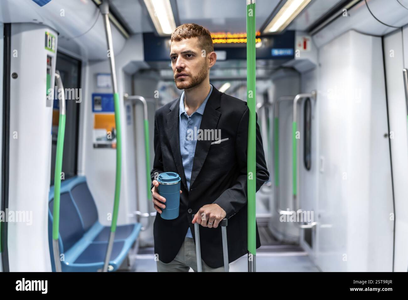 Young businessman commuting to work by subway, holding a reusable ...