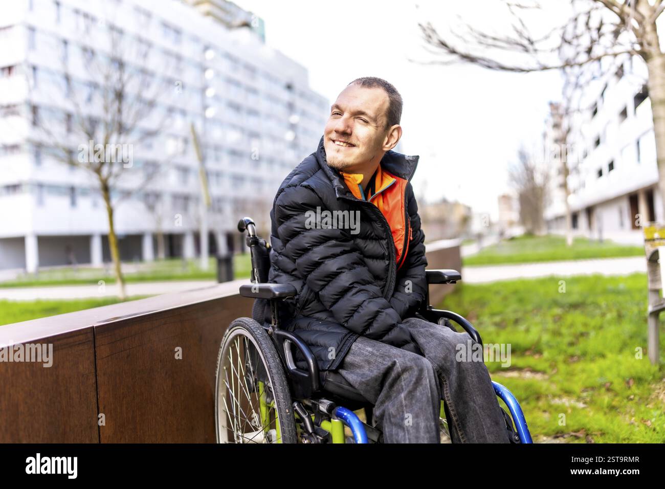 Young man using wheelchair smiling while enjoying a day out in an urban ...