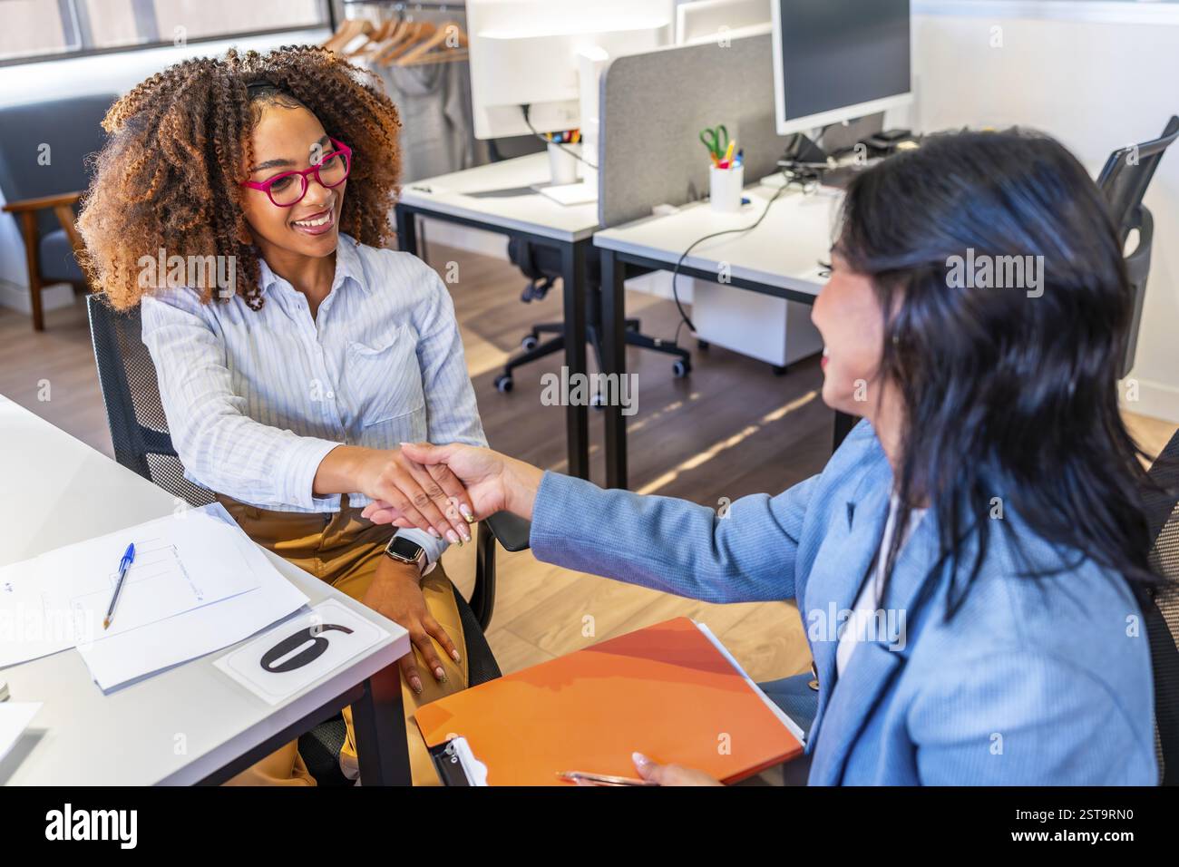 Two happy businesswomen shaking hands after a successful job interview ...