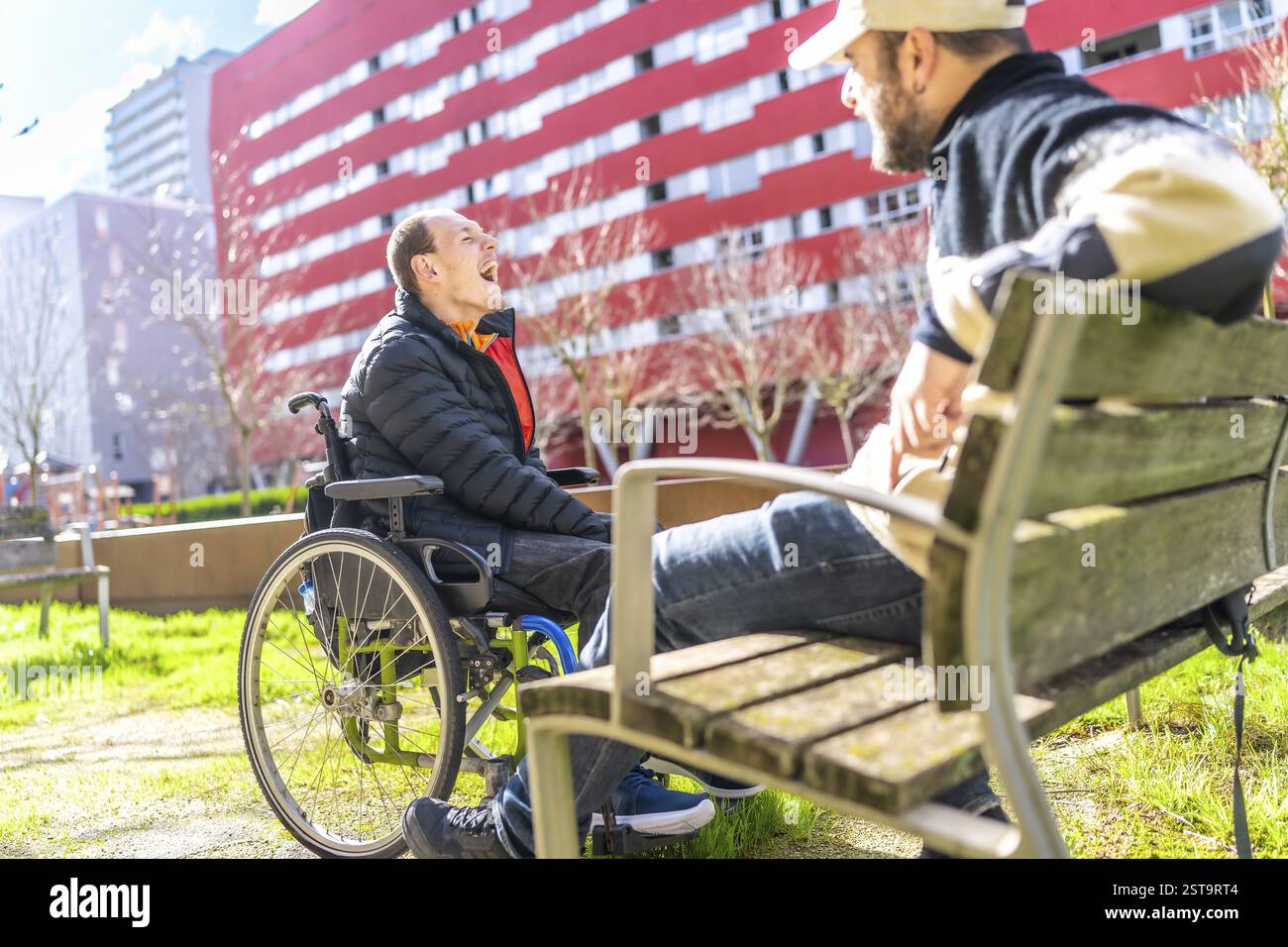 Young man using wheelchair laughing and enjoying conversation with ...