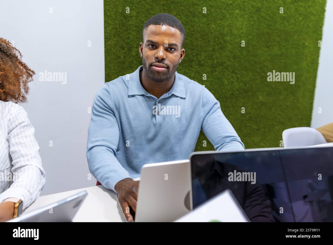 Young confident manager using laptop computer in shared workplace with ...