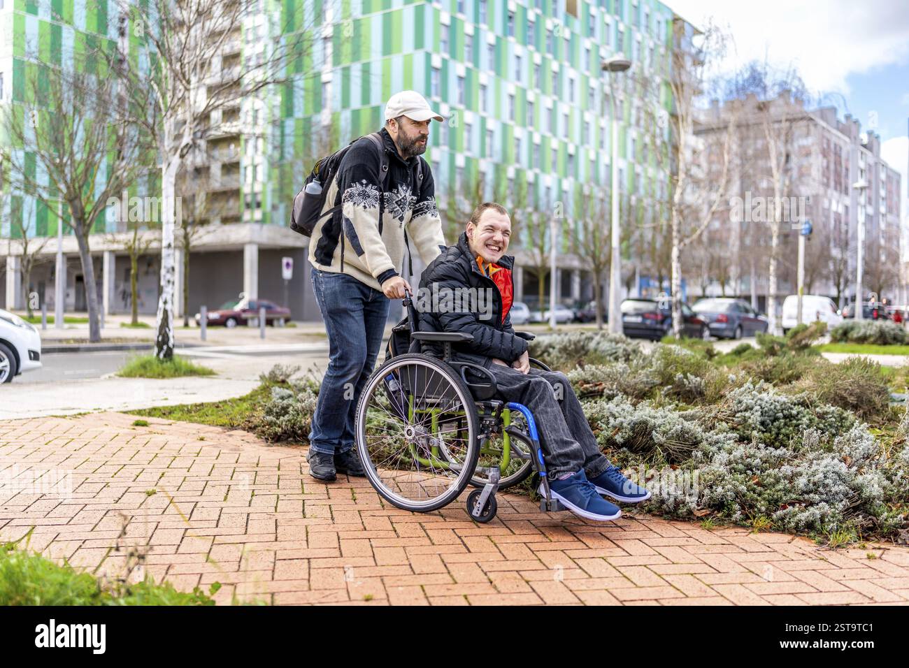 Caregiver assisting a happy disabled man in a wheelchair, enjoying an ...