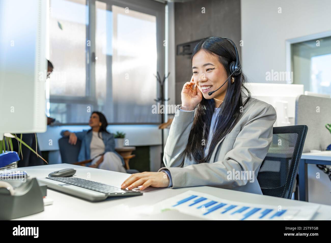 Young asian manager wearing headset working with computer in a ...