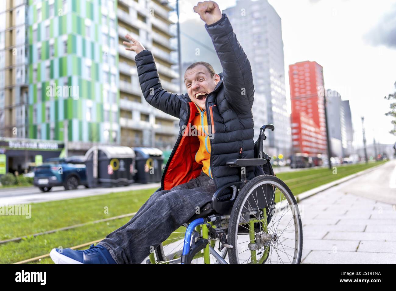 Young man in a wheelchair, raising his arms in celebration, embracing ...