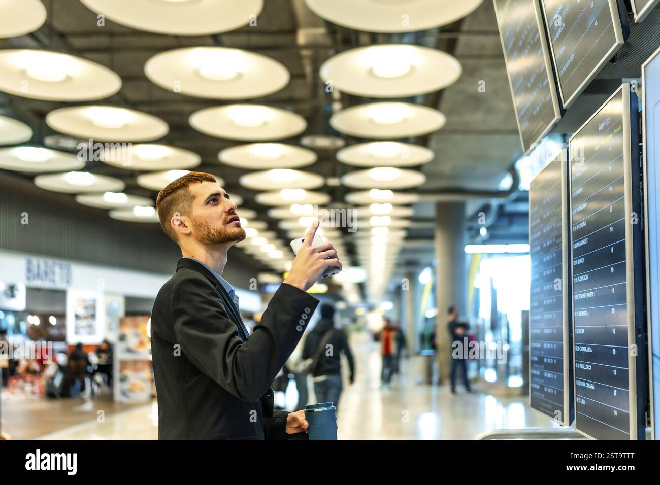Businessman consulting his smartphone and checking flight information ...