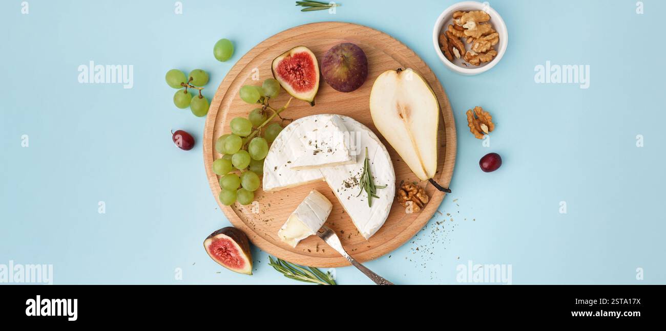 Tasty Camembert cheese, fruits and walnuts on light blue background ...
