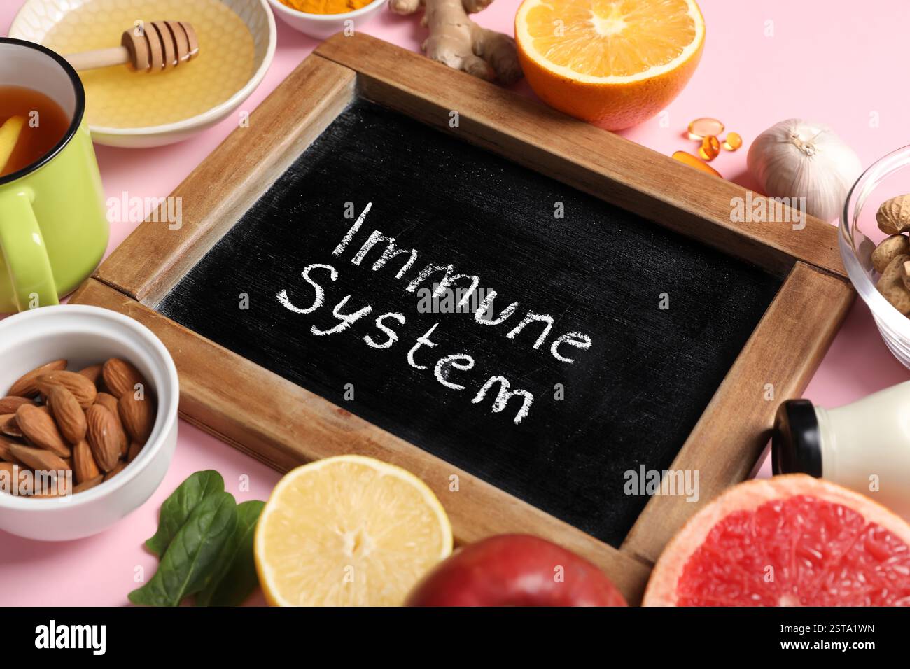 Chalkboard with text IMMUNE SYSTEM and different healthy food on pink ...