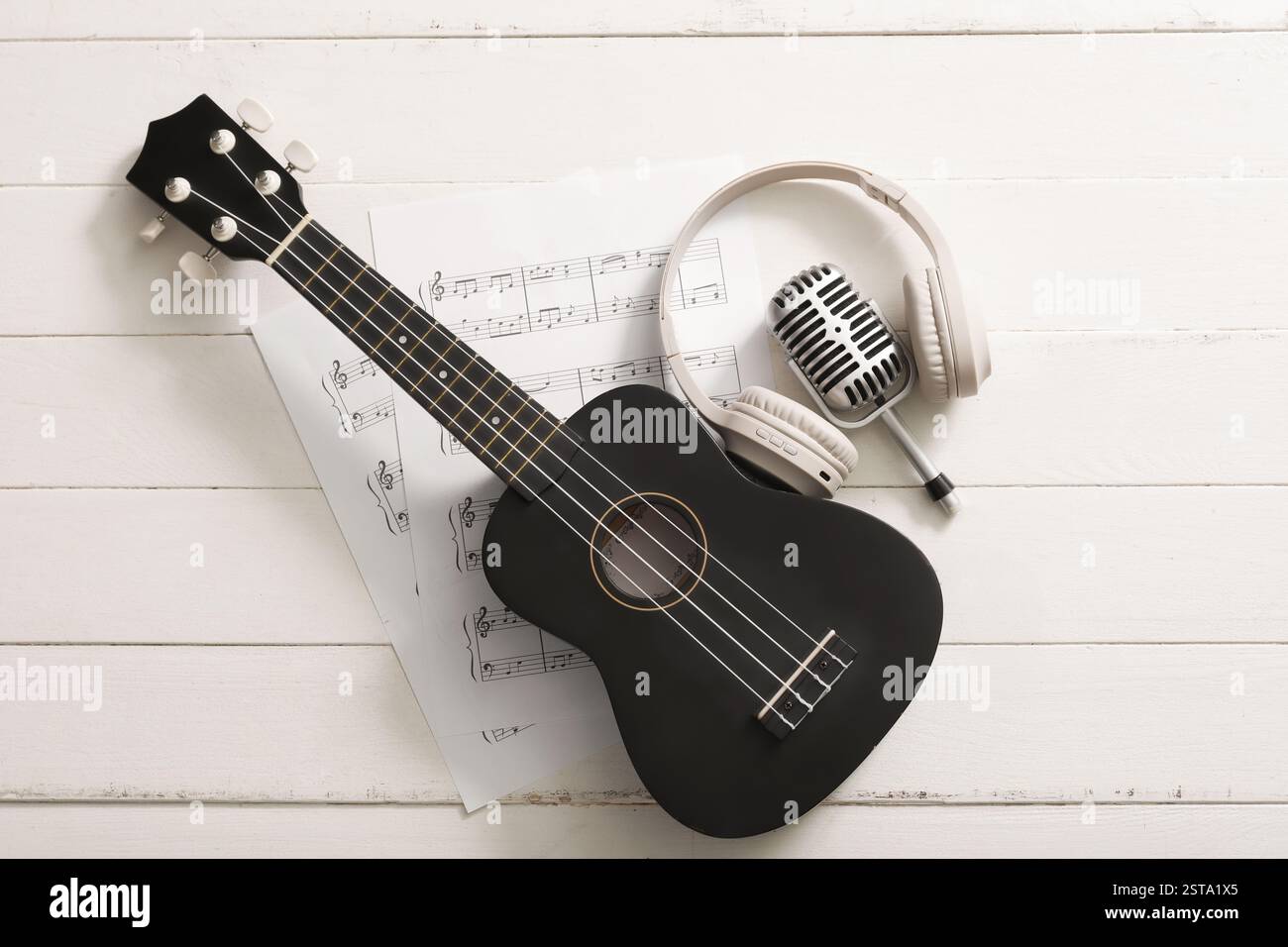 Ukulele, modern headphones, microphone and music sheets on light wooden ...