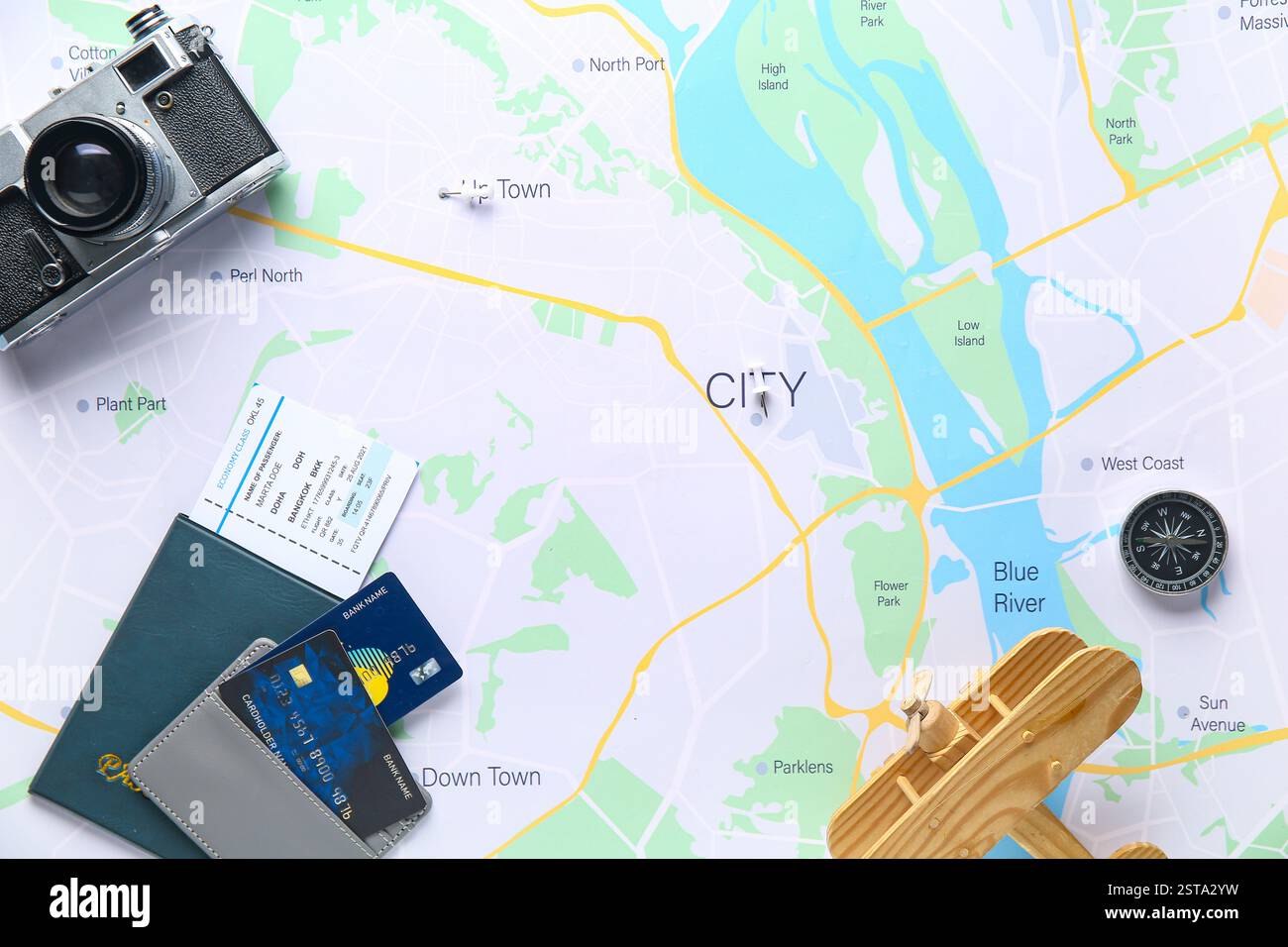 Photo camera with credit cards, wooden plane and compass on city map ...