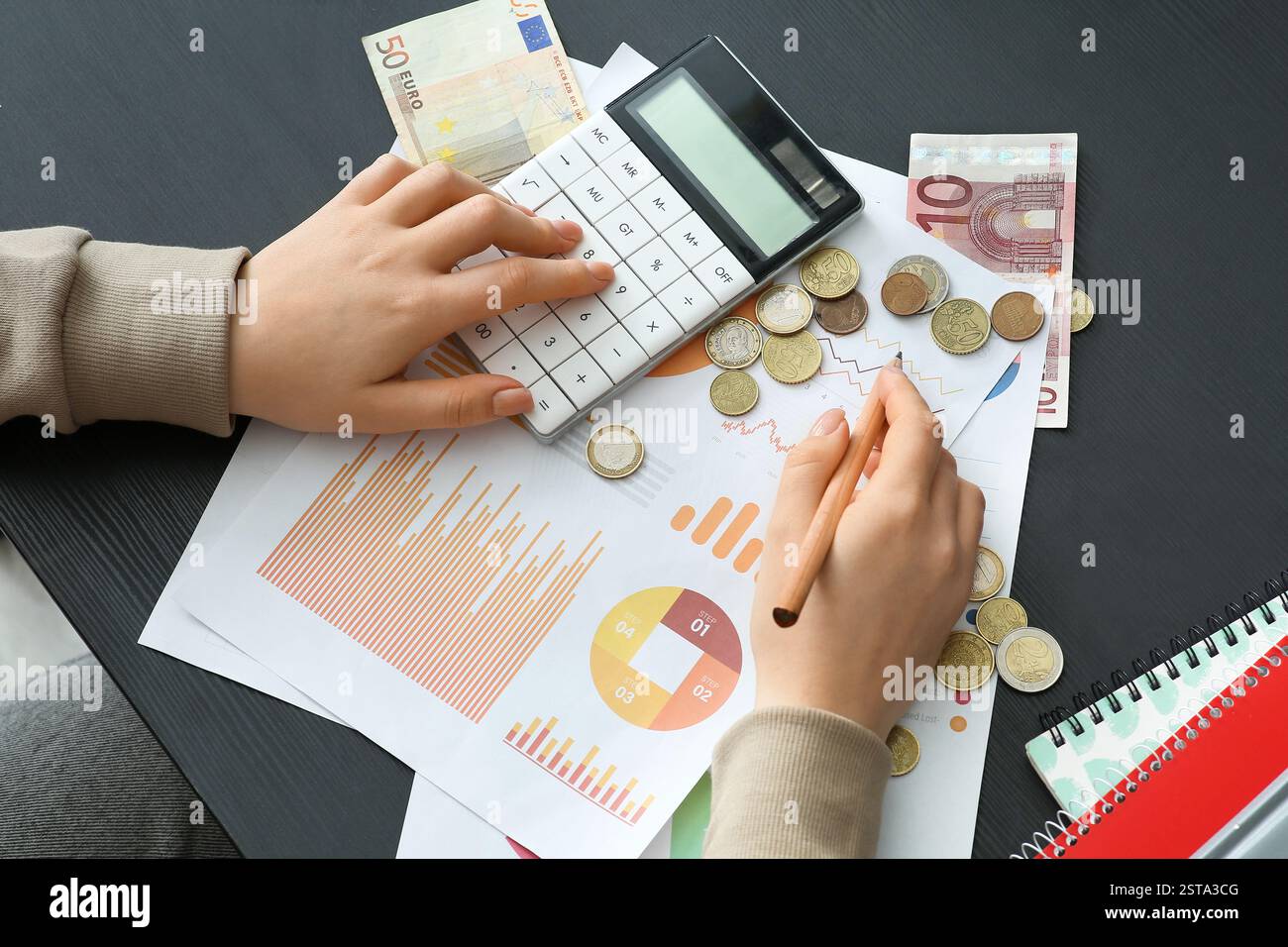 Woman with diagrams and money using calculator on dark table, closeup ...