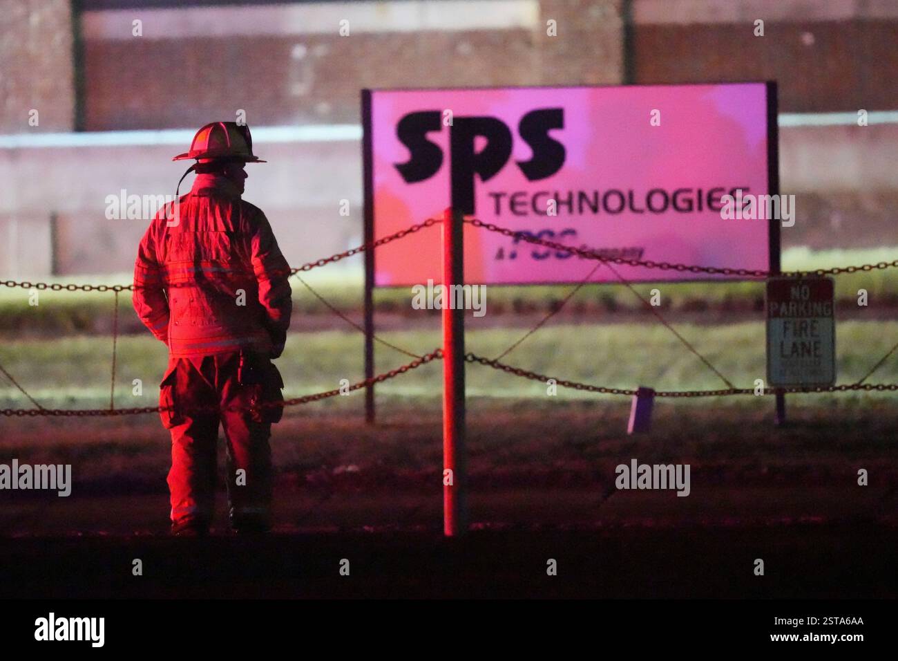 A firefighter looks on as a fire engulfs SPS Technologies in Jenkintown ...