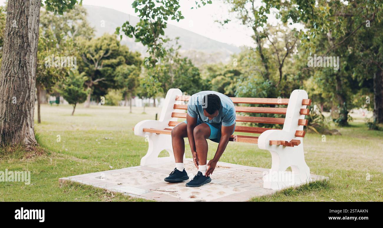 Black man, fitness and ankle pain with injury on park bench for ...