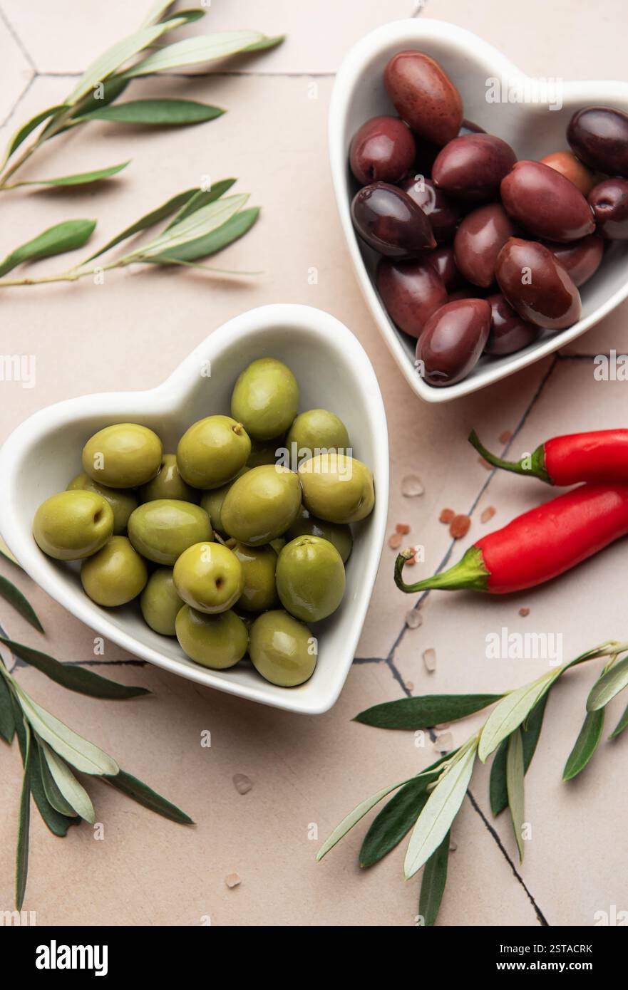 Green and black olives served in heart shaped bowls, decorated with ...
