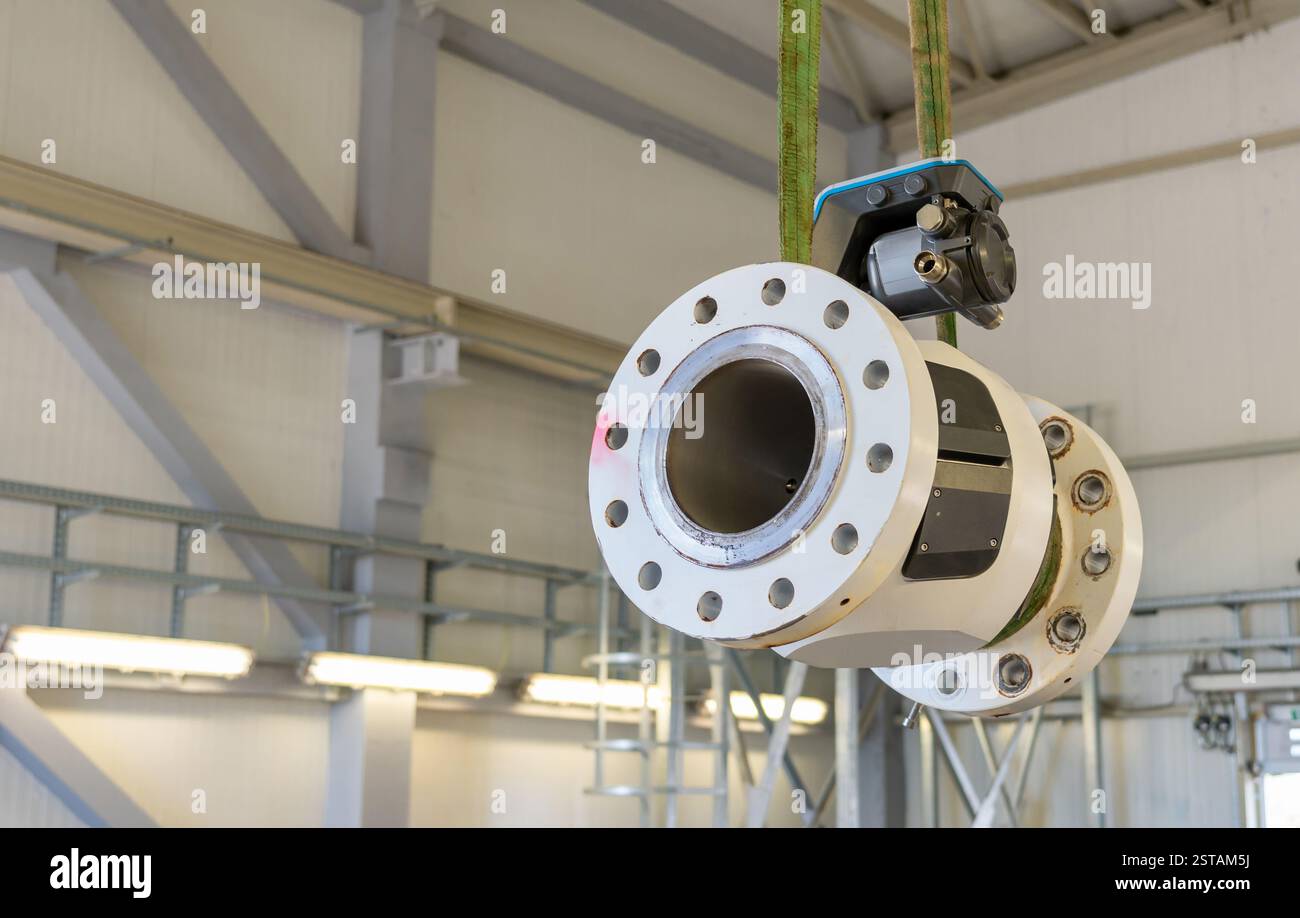 Ultrasonic flow meter being lifted for installation on a flanged pipeline in an industrial ...