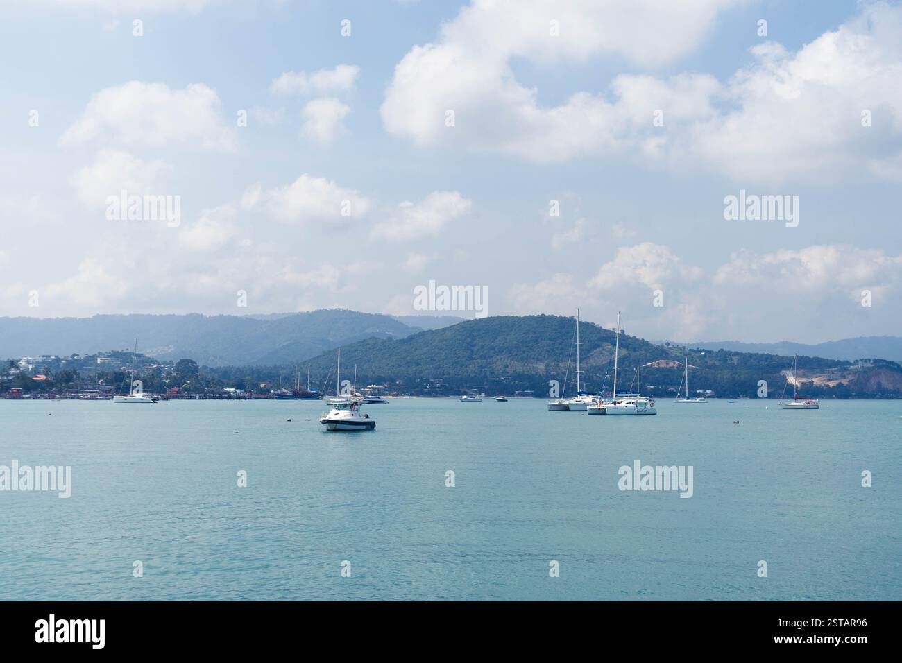 Calm waters reflect soft clouds as yachts float gently in a tranquil ...