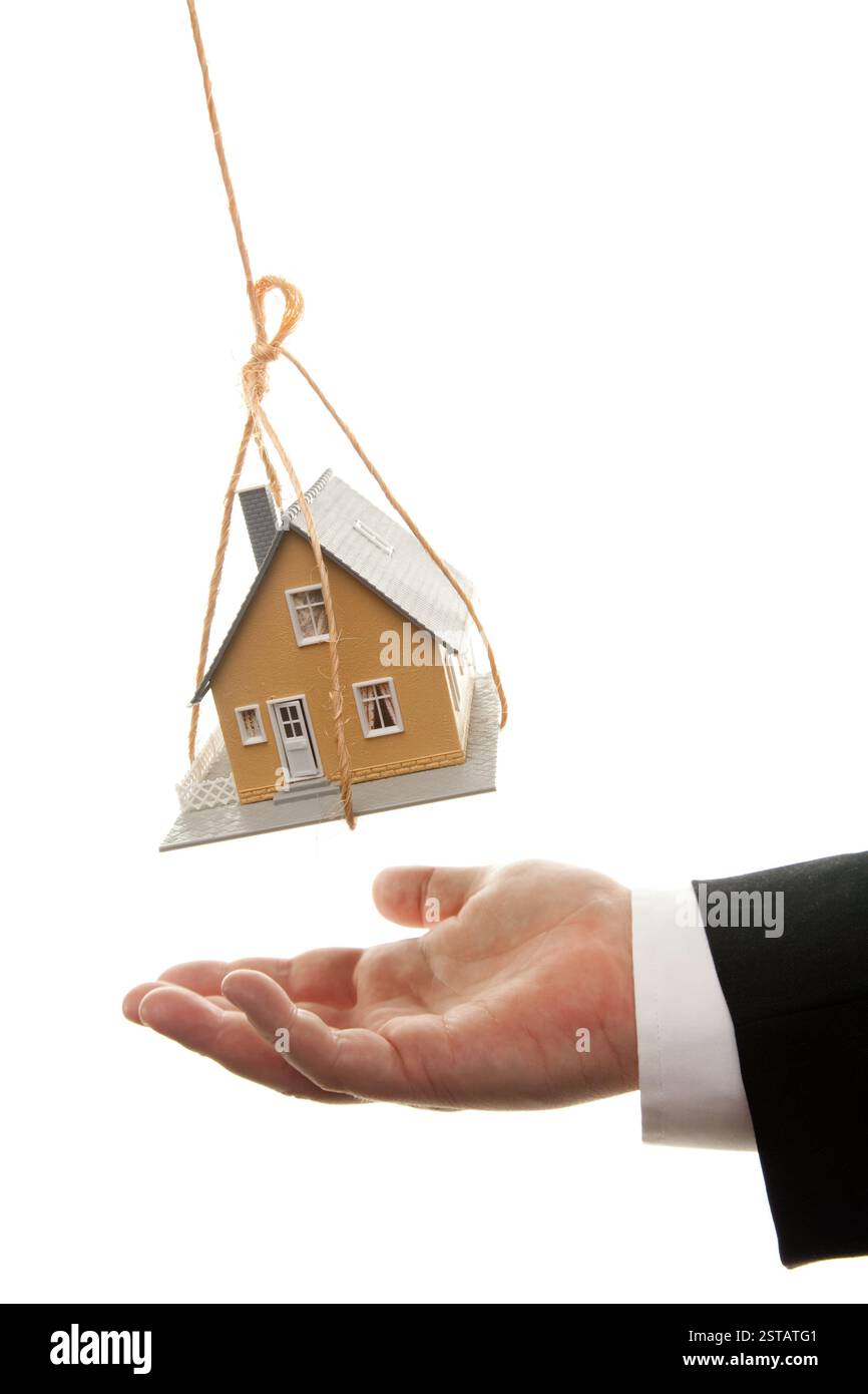 Businessman's Hand Under Dangling House Isolated on a White Background ...