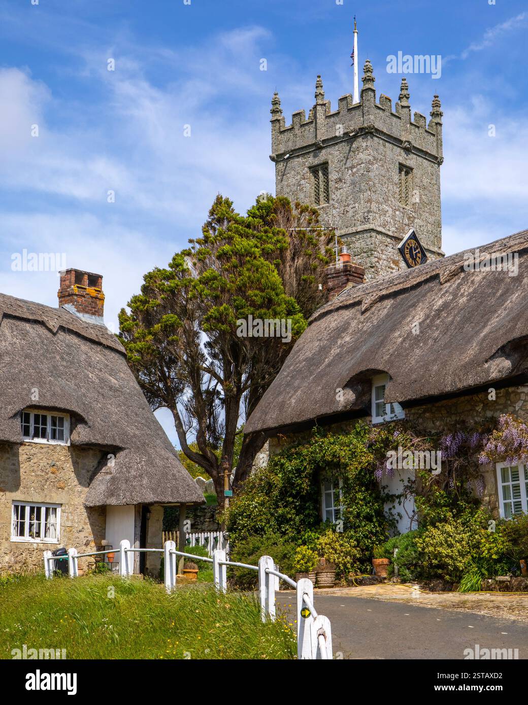 The tower of All Saints Church and beautiful thatched cottages in the ...