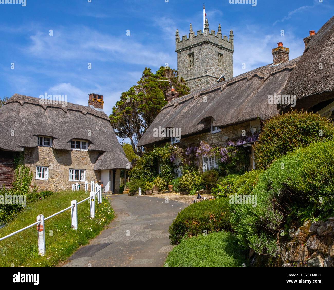 The tower of All Saints Church and beautiful thatched cottages in the ...