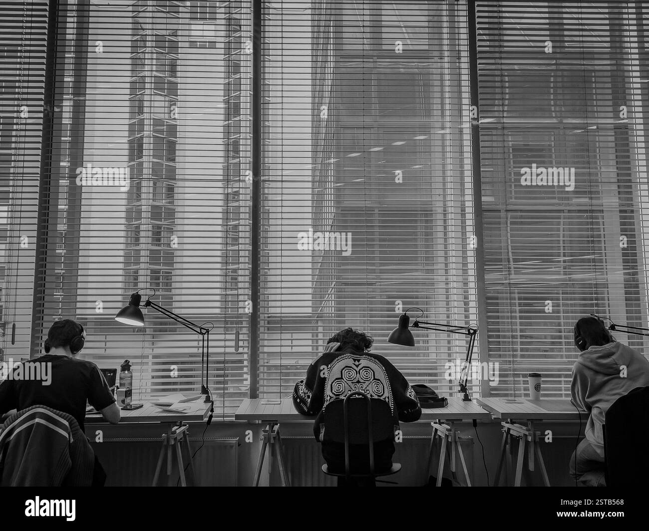 Students study in a modern urban workspace with large windows ...