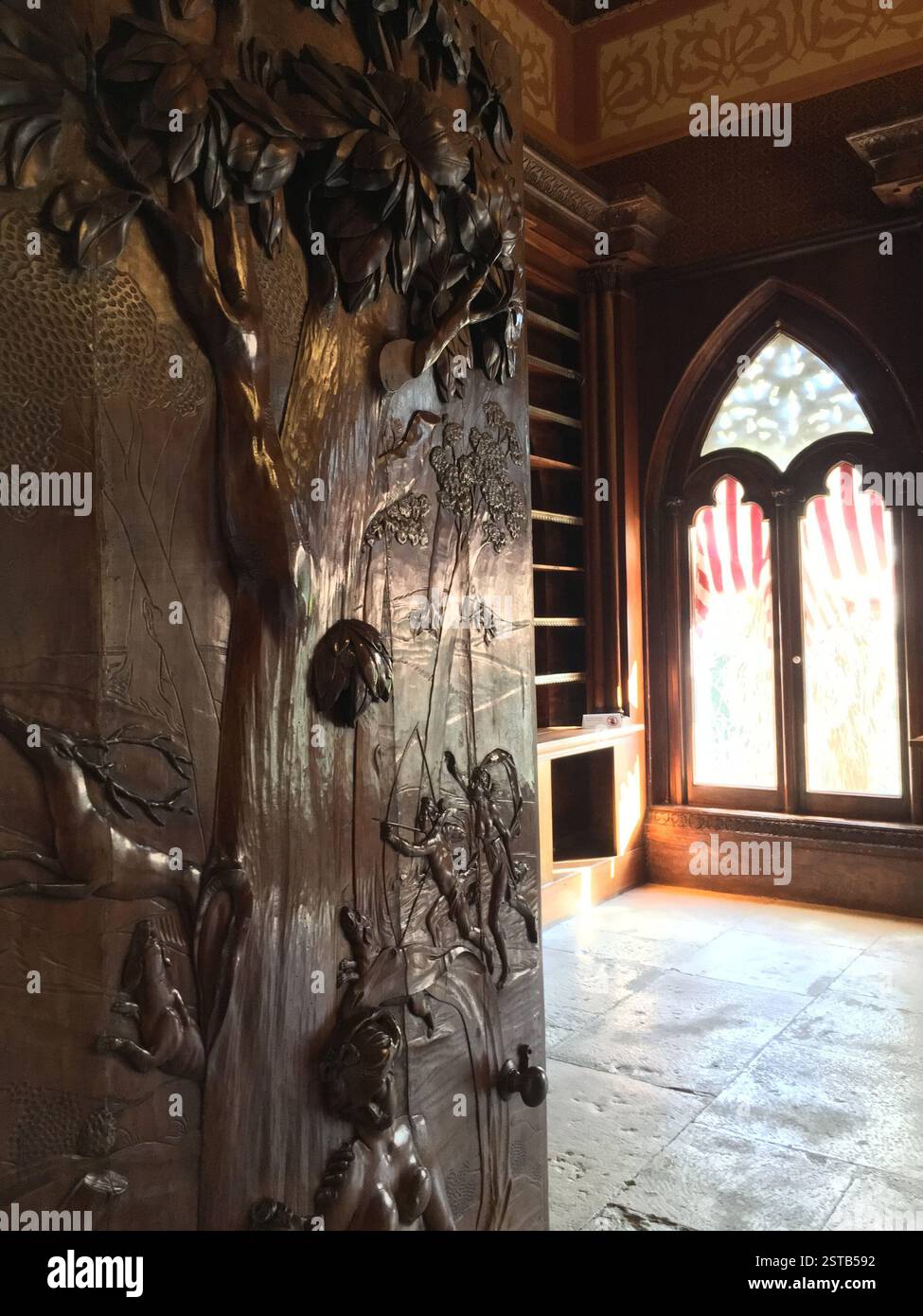 Ornate wooden door with intricate carvings depicting nature and mythological scenes. Sunlight ...