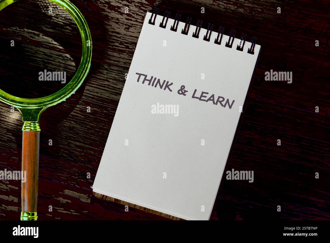 A notepad rests on a dark wooden surface, highlighting the phrase think ...