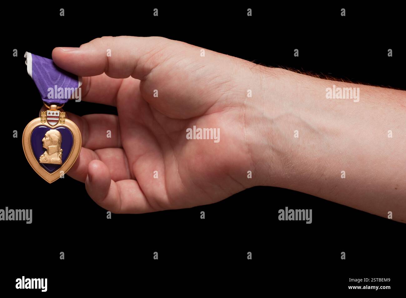 Man holding purple heart war medal on a black background hi-res stock ...