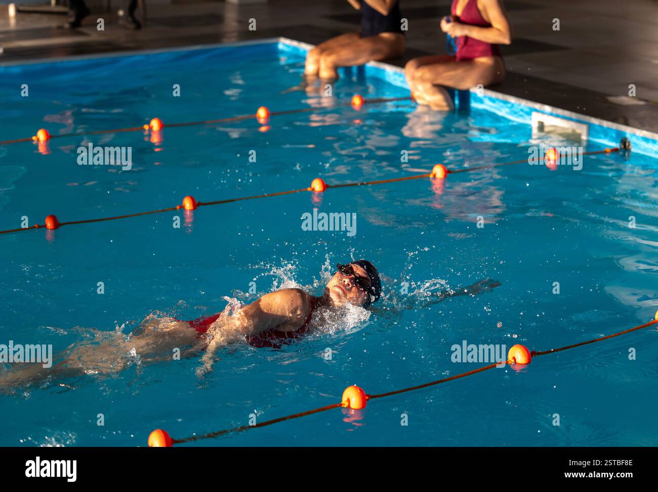 Swimmers practice in an indoor pool, showcasing skills as they glide through the water during a ...