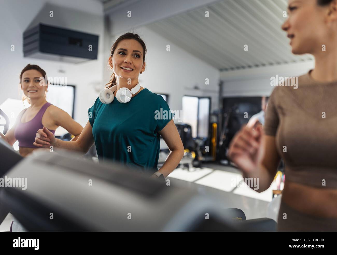 Three women are exercising on treadmills, enjoying their workout in a ...