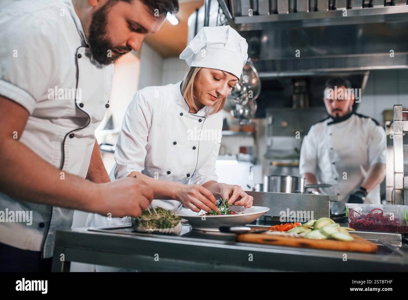 Team making salad. Professional chef preparing food in the kitchen ...