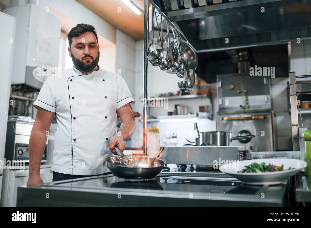 Method of cooking by igniting meal. Professional chef preparing food in ...