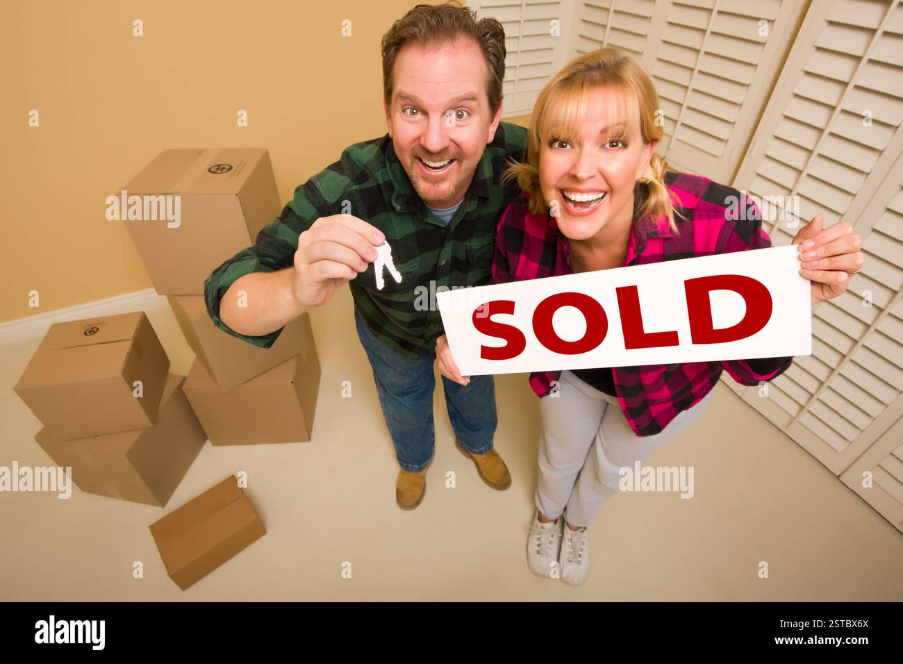 Goofy Couple Holding Key and Sold Sign Surrounded by Boxes Stock Photo ...