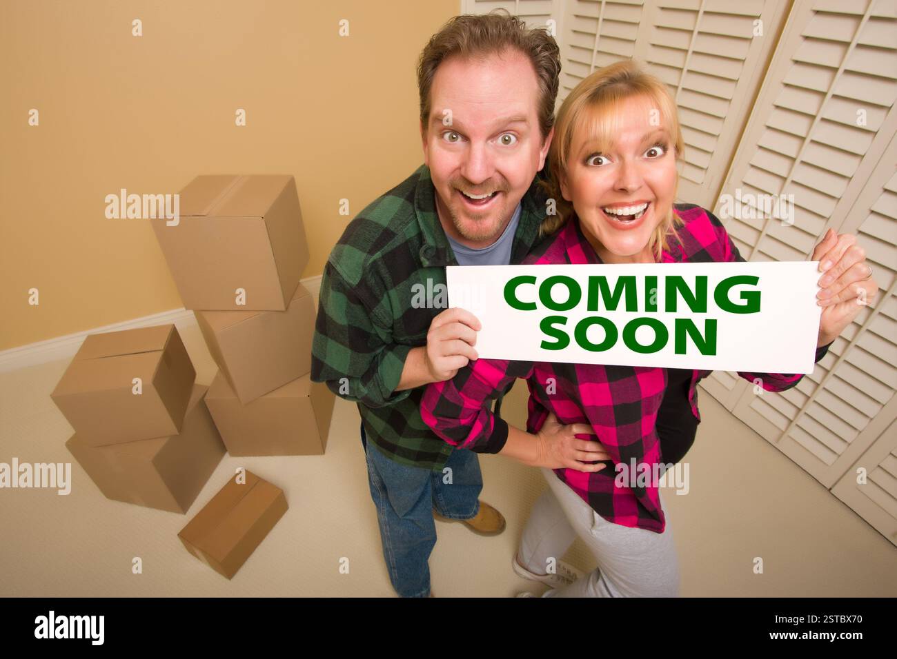 Goofy Couple Holding Coming Soon Sign in Room with Boxes Stock Photo ...