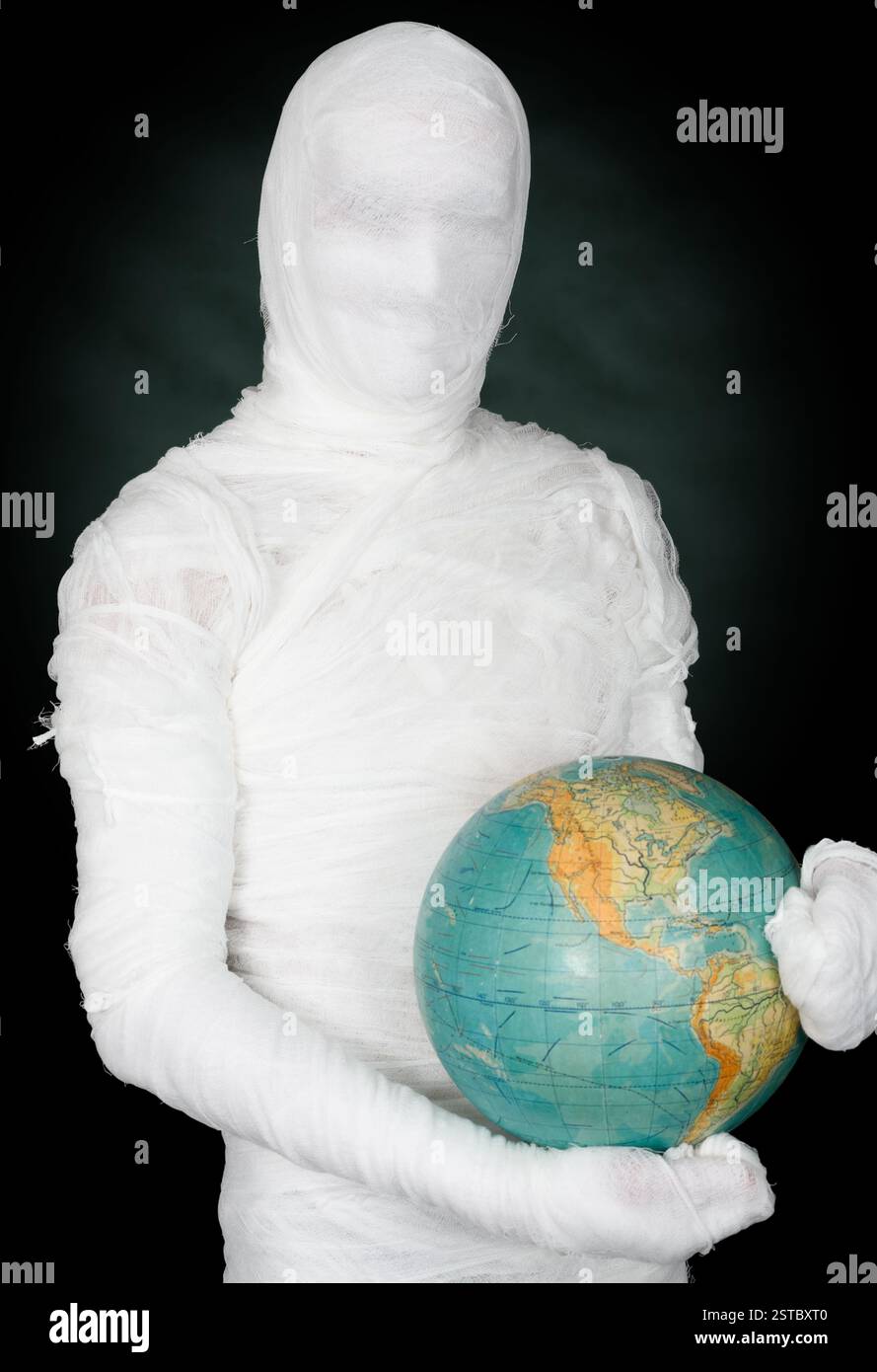 Man in costume mummy and terrestrial globe Stock Photo - Alamy