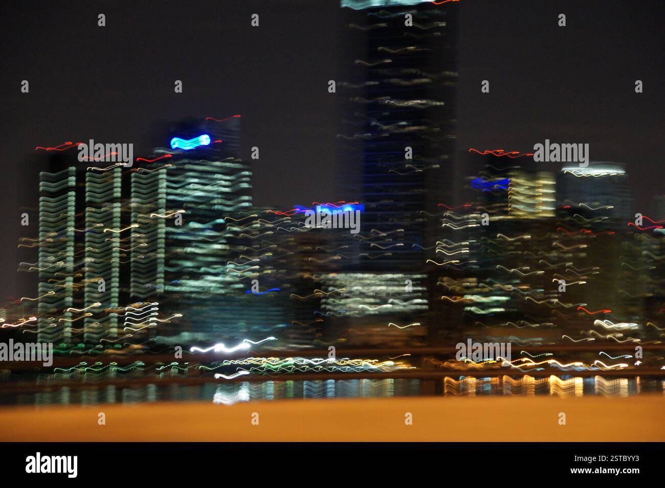 A hazy Miami skyline stretches across the night. Glowing windows of ...