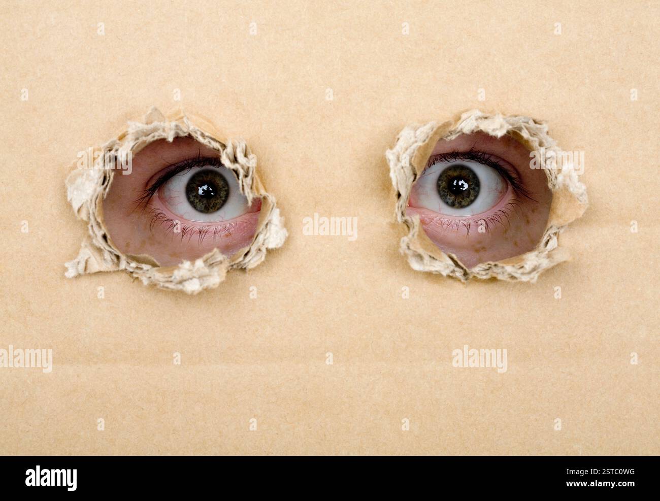 Eye looking from a holes in a cardboard Stock Photo - Alamy