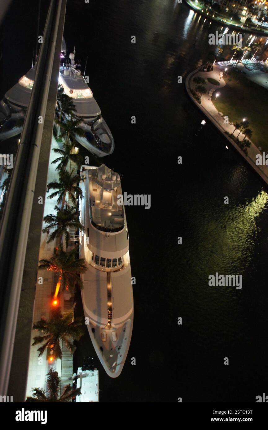 Aerial view of Miami harbor at night, two illuminated yachts docked ...