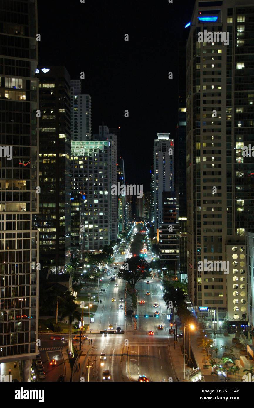 Busy city street Miami. Illuminated buildings line the street, cars ...