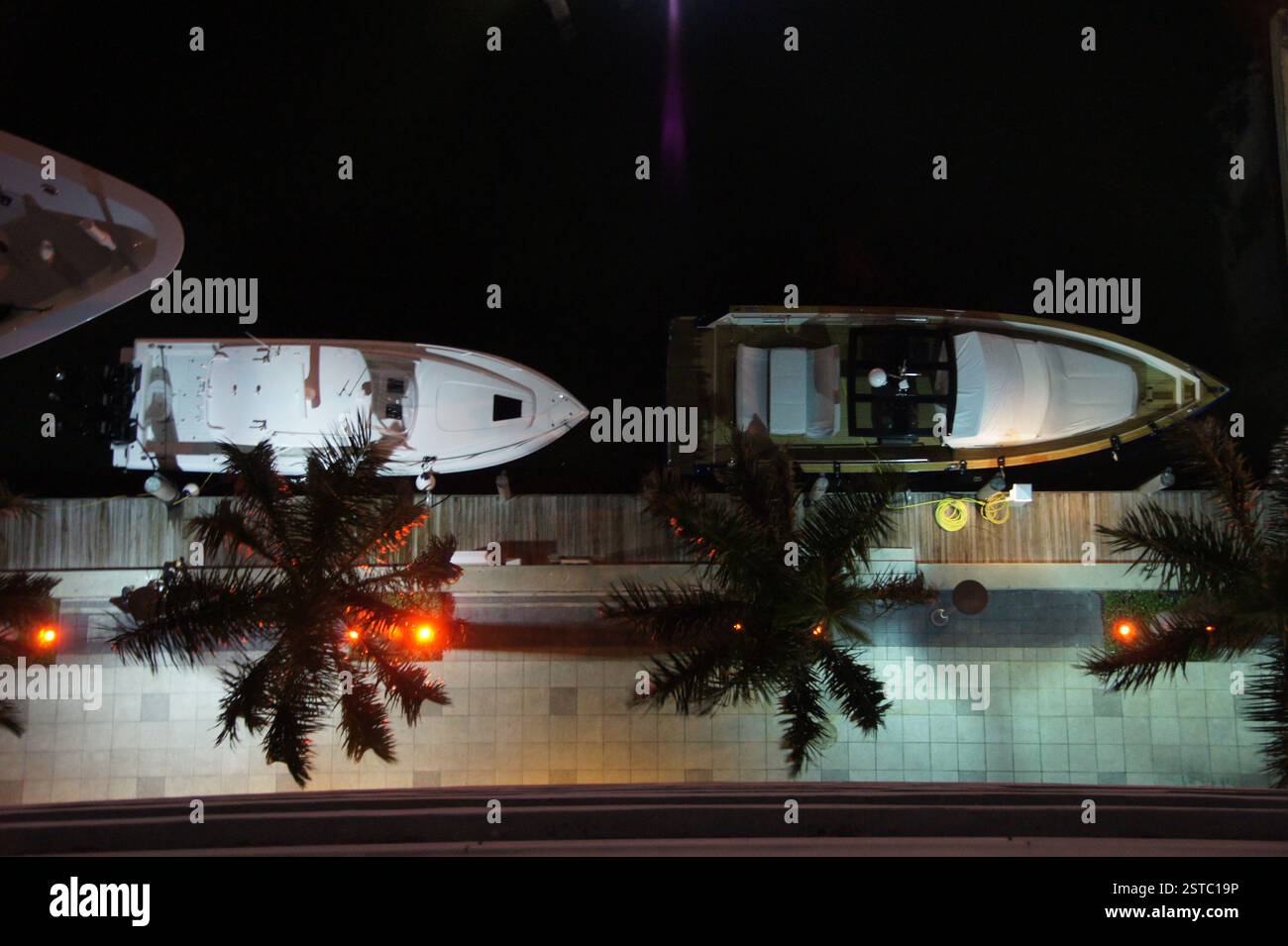 Miami. Two docked boats at night in a harbor with palm trees in the ...