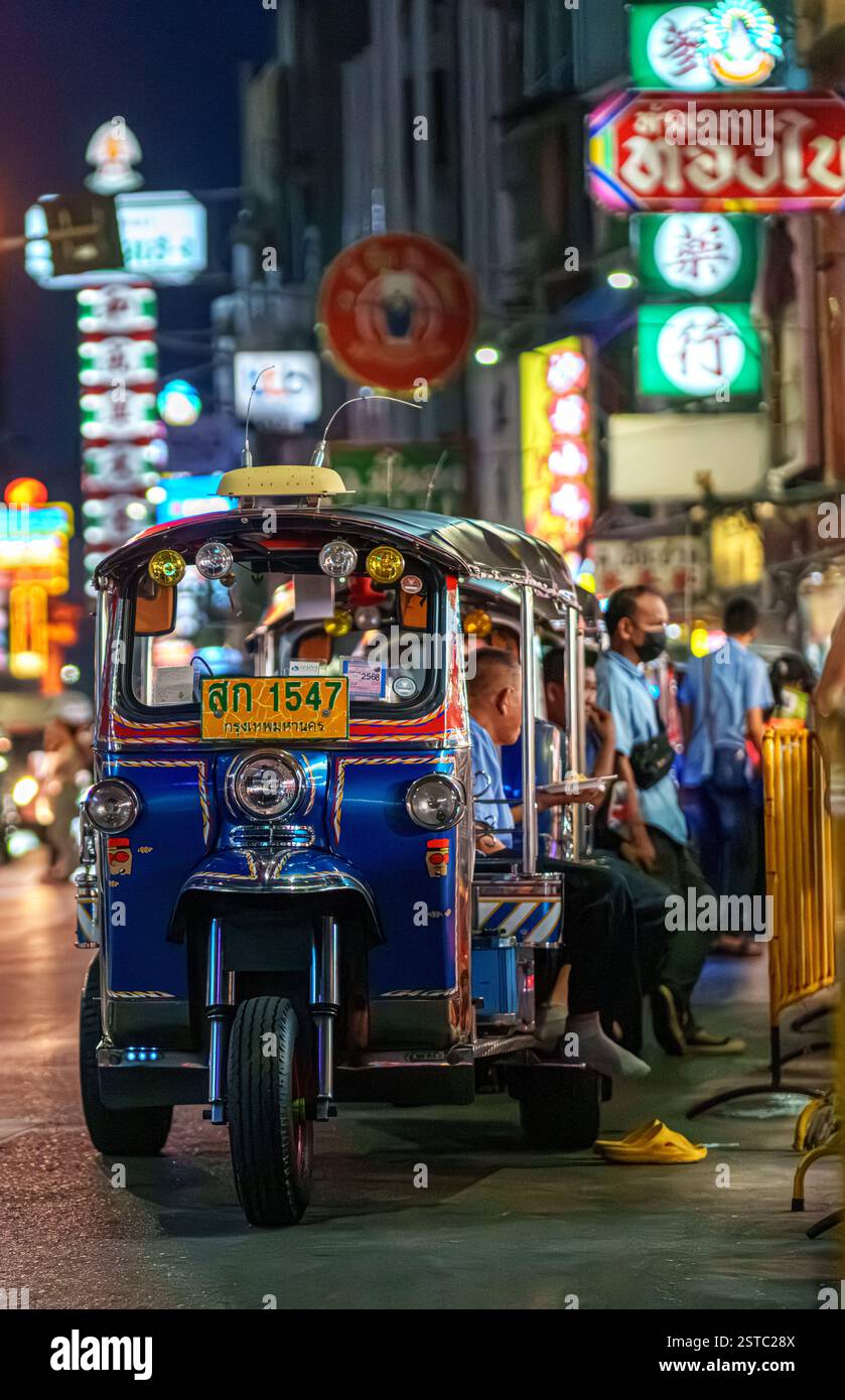 A colorful tuk-tuk, a symbol of Thai urban transport, is captured at night in the heart of ...