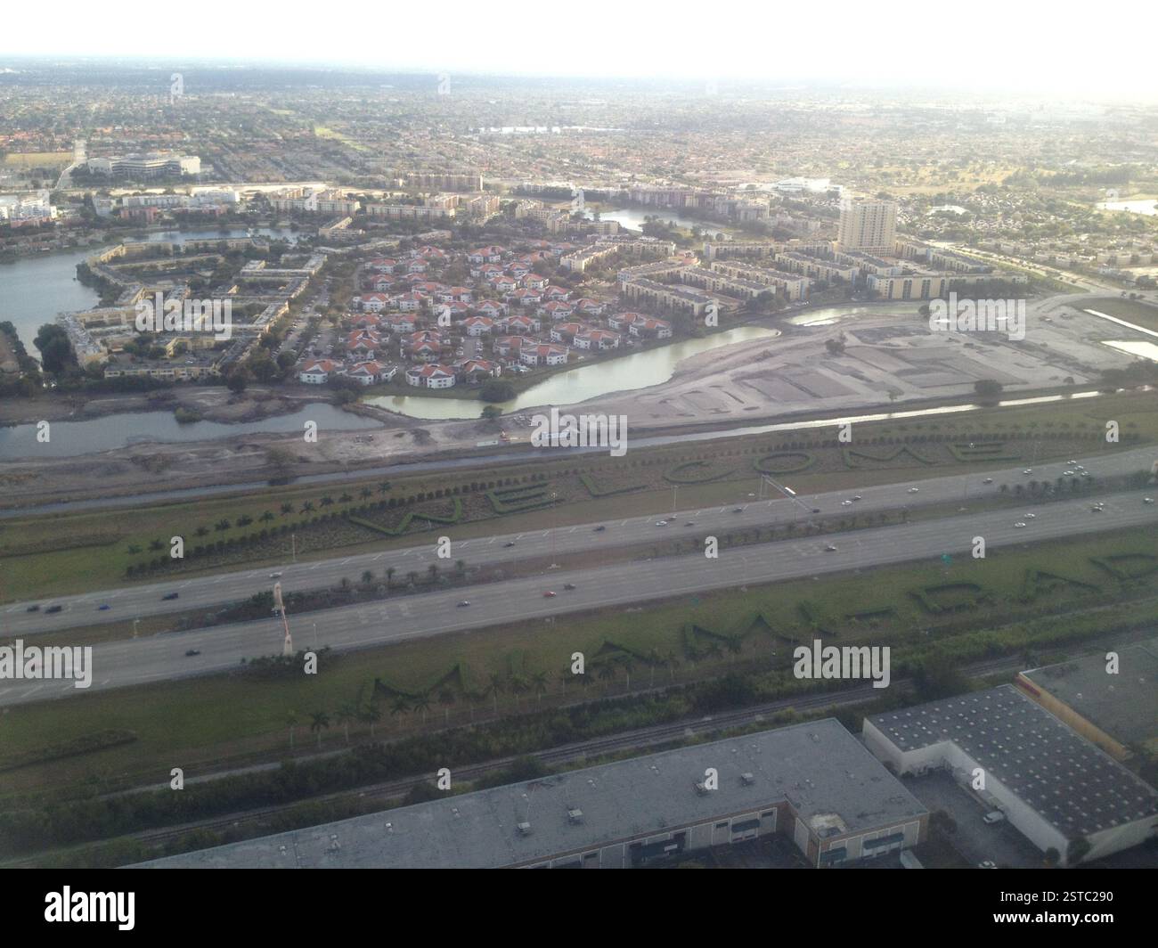 Aerial view of a Miami highway with welcome sign, surrounded by trees ...