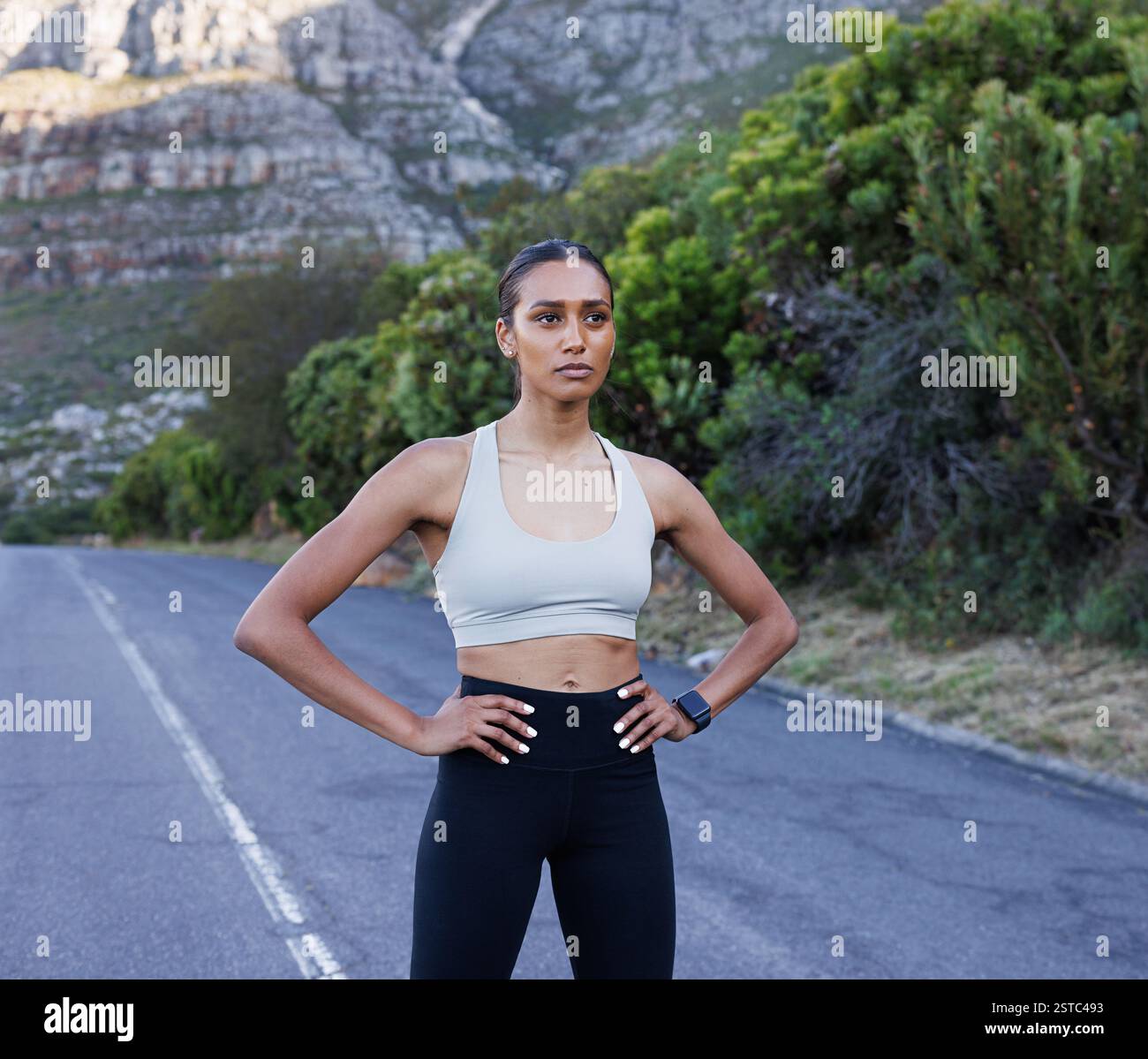 Slim confident woman in fitness attire with hands on her hips standing ...