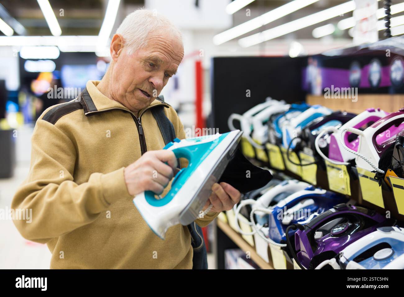 Senor man pensioner buying iron in showroom of electrical appliance ...