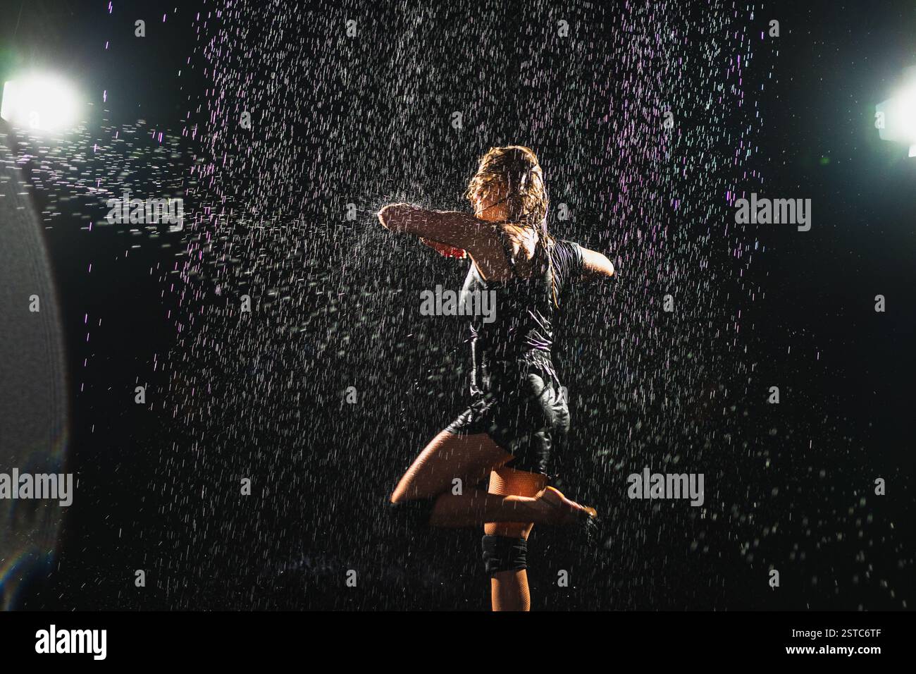 Contemporary woman dancer posing in rain water on black background ...