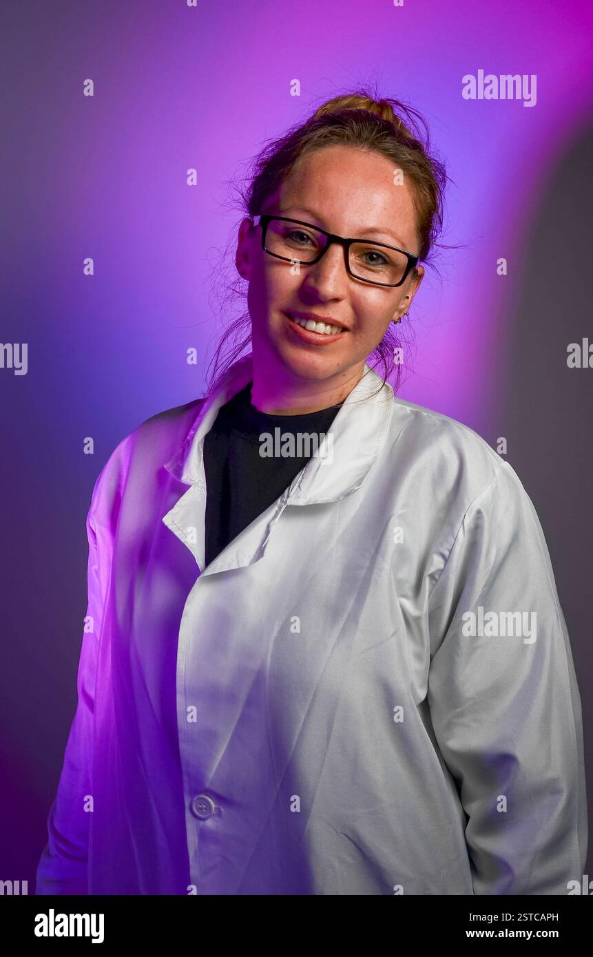 Female scientist smiling in a purple laboratory setting, conveying ...