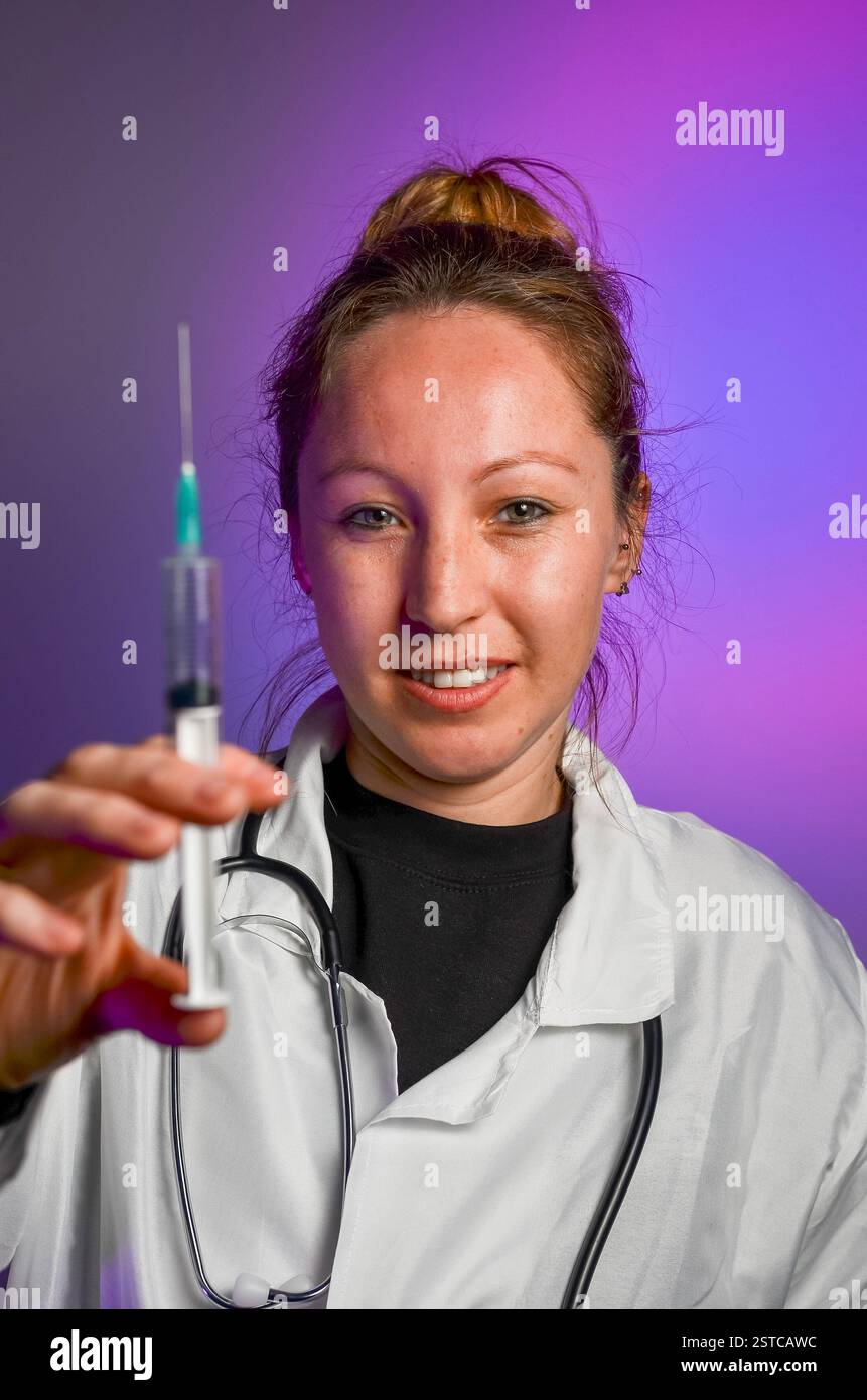 Smiling doctor holding a syringe containing a vaccine, promoting ...