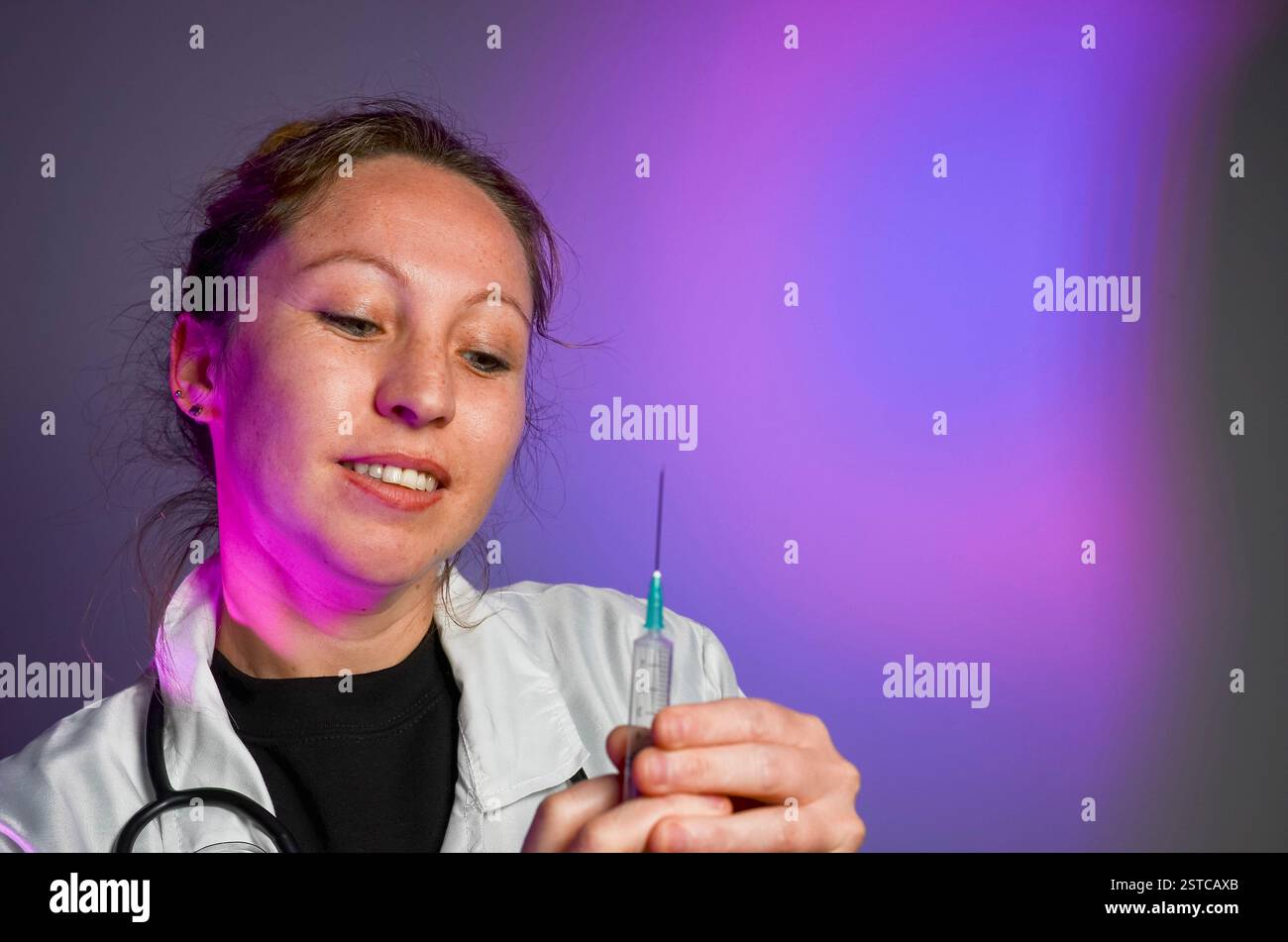 Doctor wearing lab coat and stethoscope preparing a syringe for ...