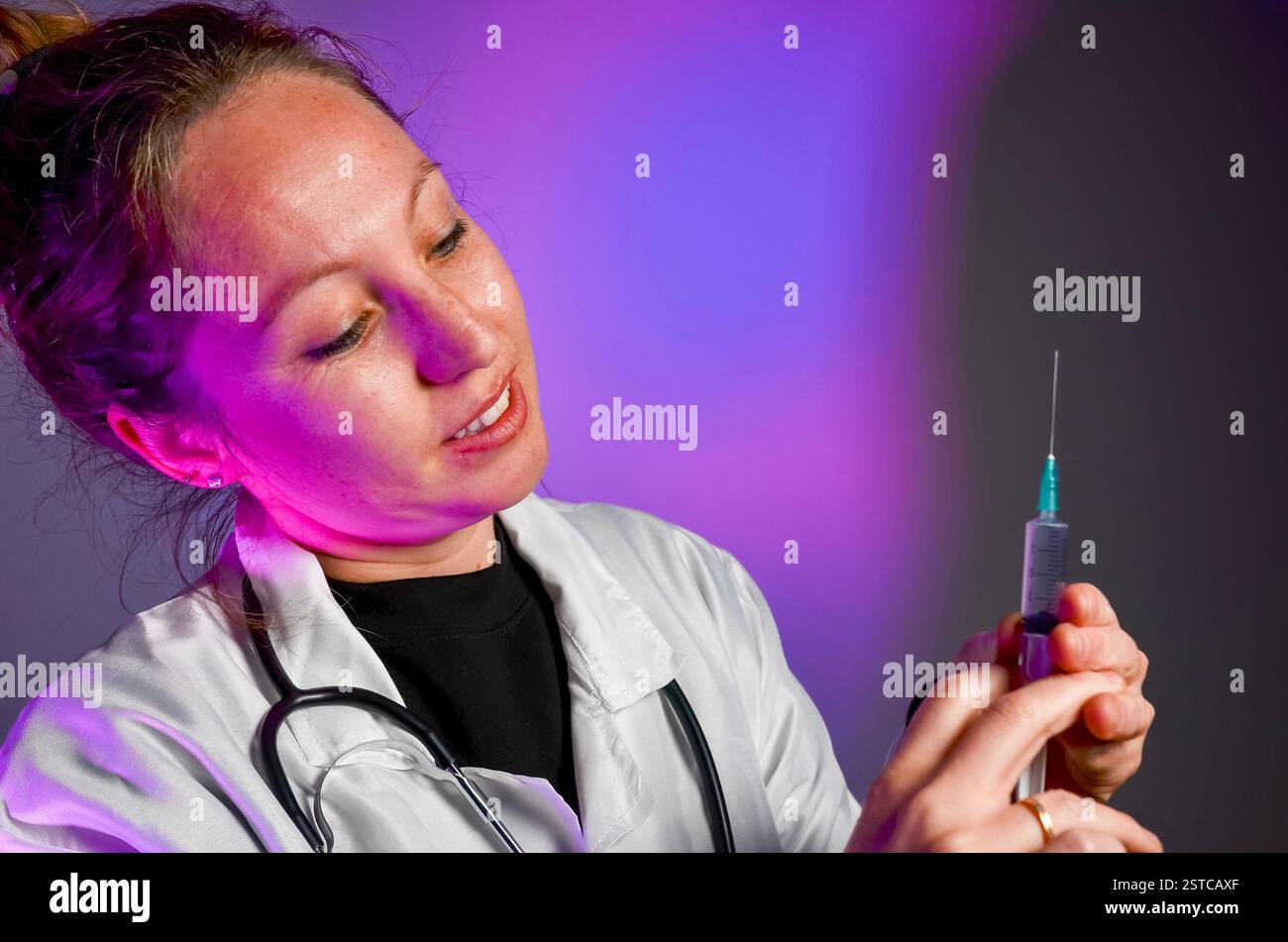 Doctor preparing a syringe for injection, holding it carefully with ...